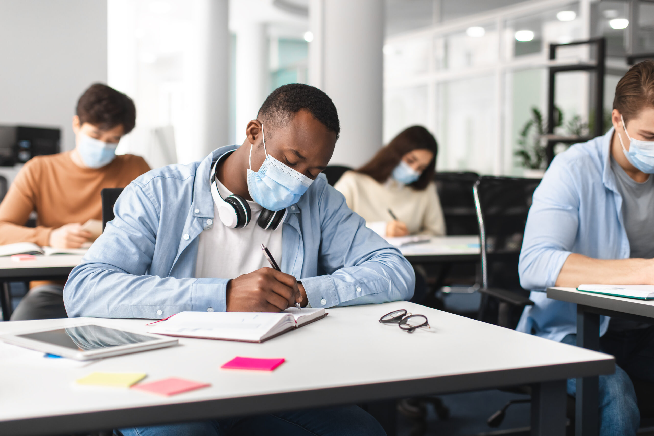 Black male student in mask sitting at desk and writing - disAbility Law ...